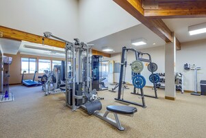 Uma academia com diversos equipamentos de exercícios, incluindo aparelhos de musculação e pesos livres.