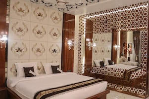 Quarto de hotel com uma cama grande, um espelho e papel de parede estampado.
