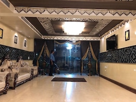 Um hall de entrada com um lustre, um sofá e um painel decorativo.