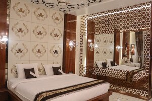 Quarto de hotel com uma cama grande, um espelho e papel de parede estampado.