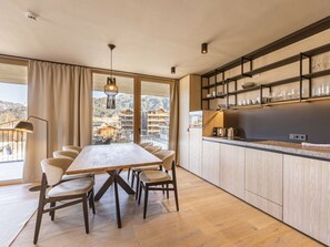 Cozinha moderna com mesa e cadeiras de madeira, adega embutida e vista para um resort de montanha.