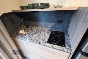 Cozinha compacta com fogão embutido, pia e bancada de madeira.