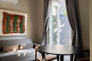 Quarto com sofá cinzento, mesa redonda e uma grande pintura abstrata.