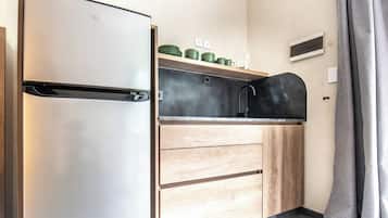 Cozinha compacta com geladeira embutida, pia e armários de madeira.