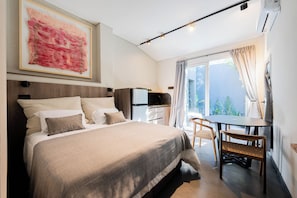 Quarto de hotel moderno com uma cama grande, uma escrivaninha e vista para o verde.