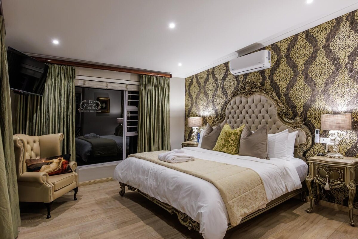 Um quarto espaçoso com uma cama grande, um chaise-lounge, uma toucador com espelho e uma janela com cortinas.