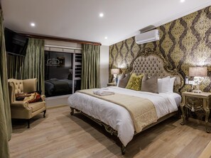 Um quarto espaçoso com uma cama grande, um chaise-lounge, uma toucador com espelho e uma janela com cortinas.