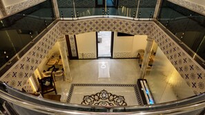 Um átrio espaçoso com teto alto, padrões de azulejos elaborados e área central aberta com assentos.