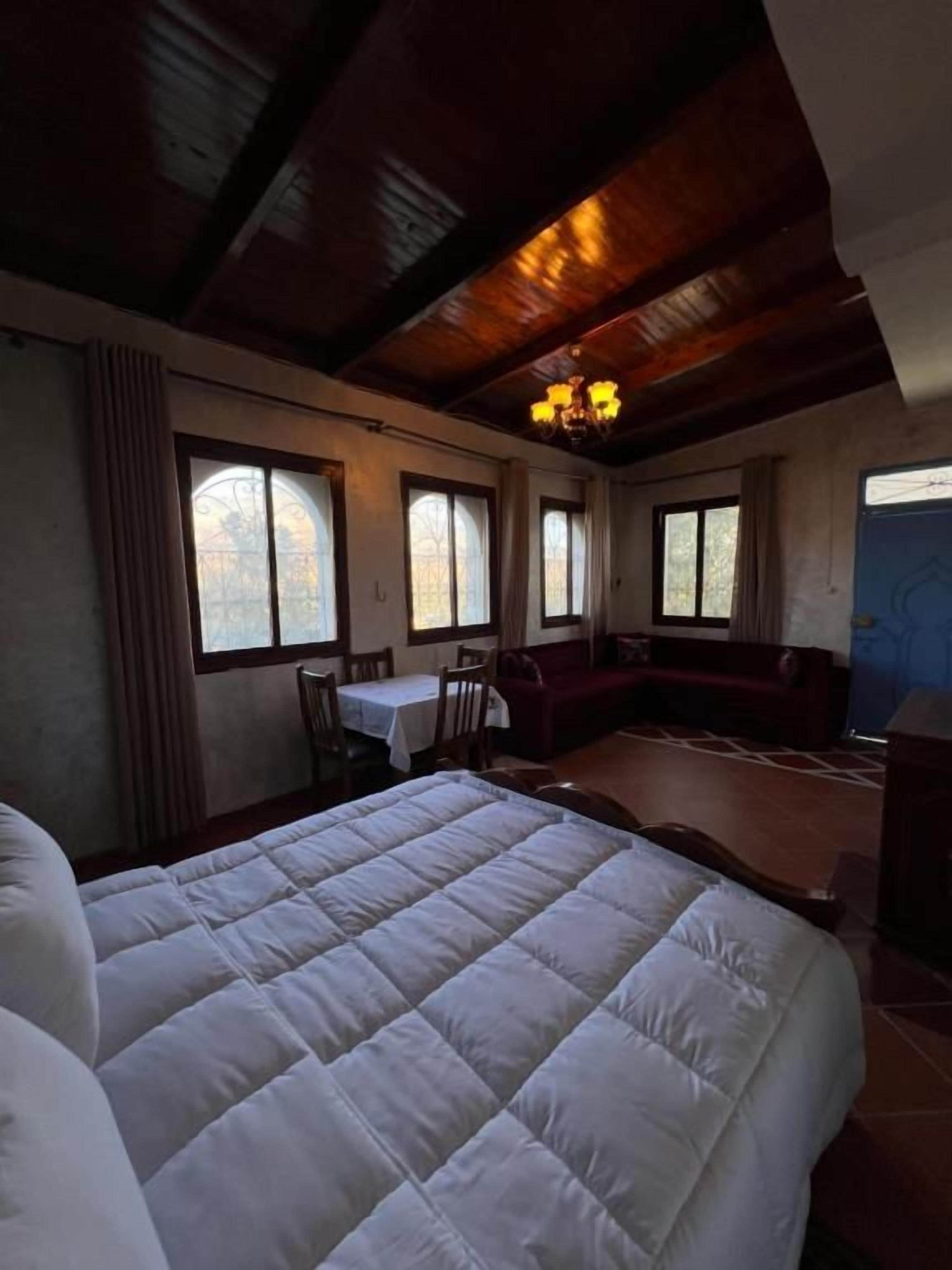 Quarto com cama grande, mesa de jantar e área de estar.