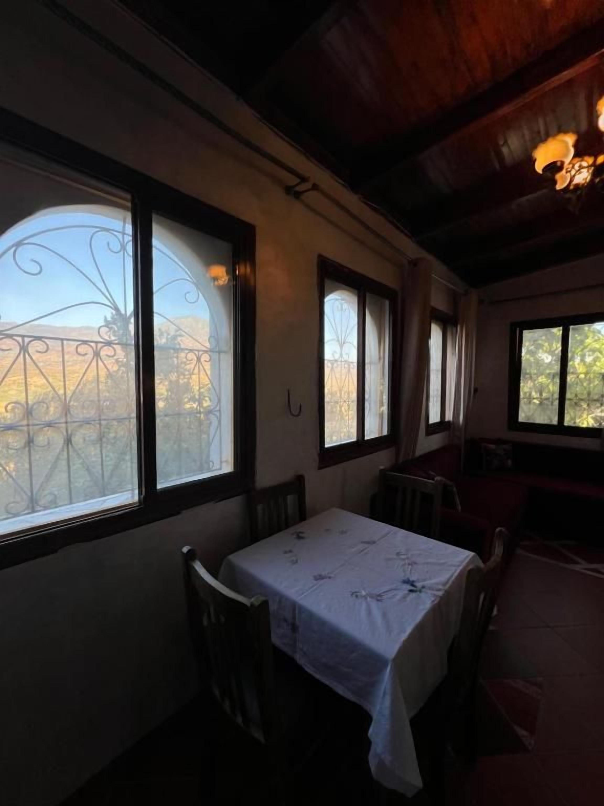 Uma sala de jantar com mesa e cadeiras, janelas amplas com vista e teto de madeira.