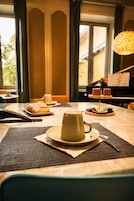 Uma mesa de jantar com uma xícara de café, um pastel e acompanhamentos.