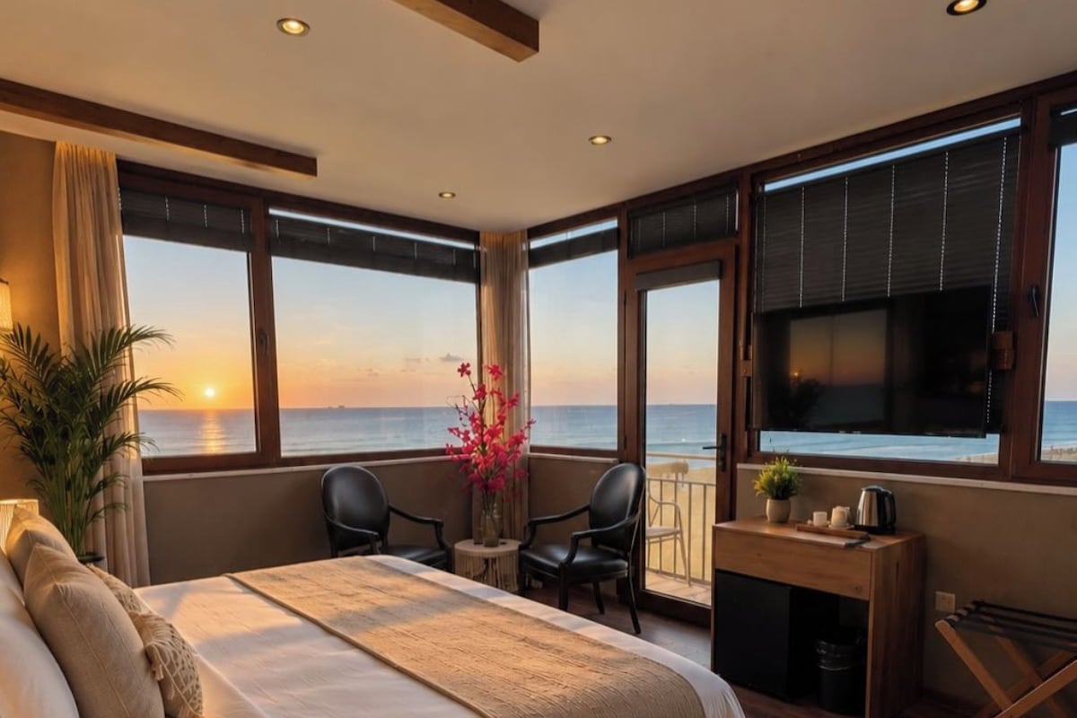 Quarto com cama grande, escrivaninha e vista para o mar.