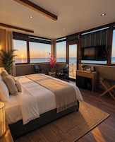 Quarto com cama grande, escrivaninha e vista para o mar.
