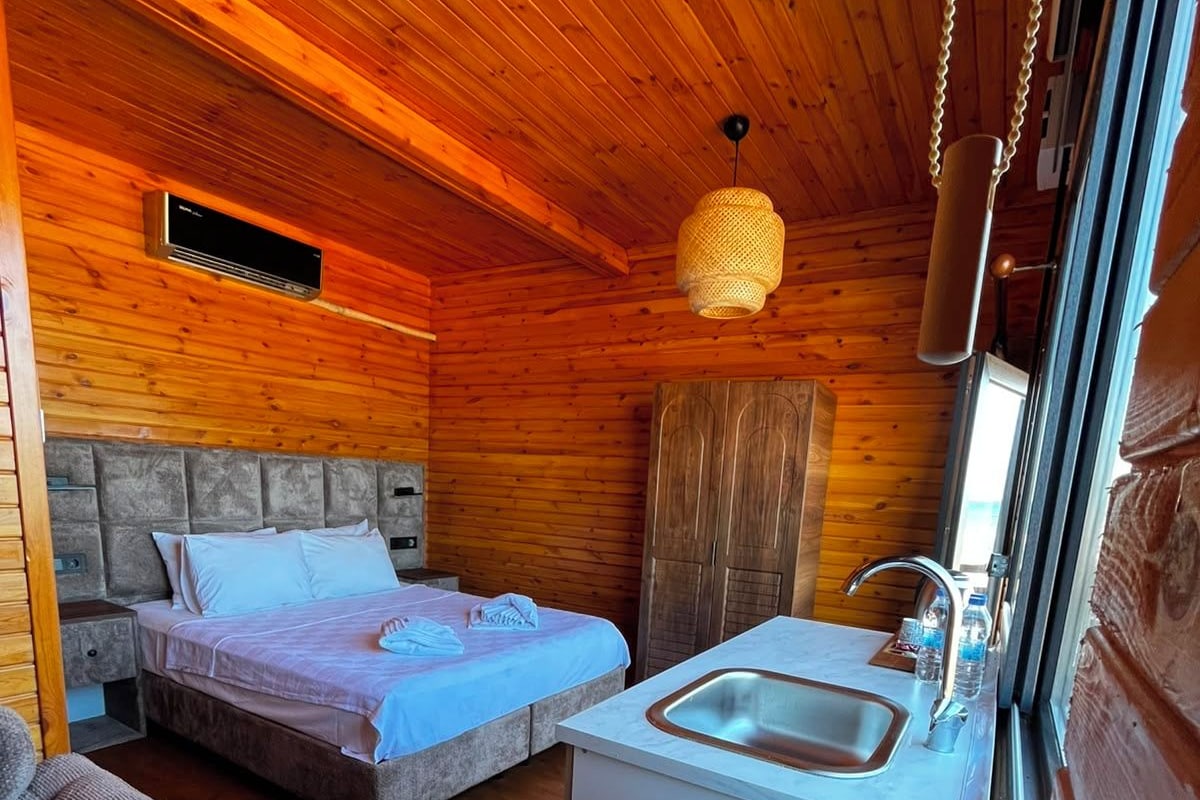 Interior acolhedor de uma cabana, com cama, sofá, pia e mesa de jantar.