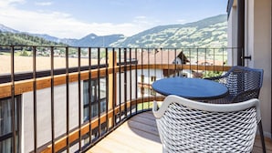 Varanda com vista para montanhas, uma mesa e uma cadeira.