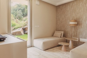 Quarto moderno com sofá, mesa redonda pequena e luminária.