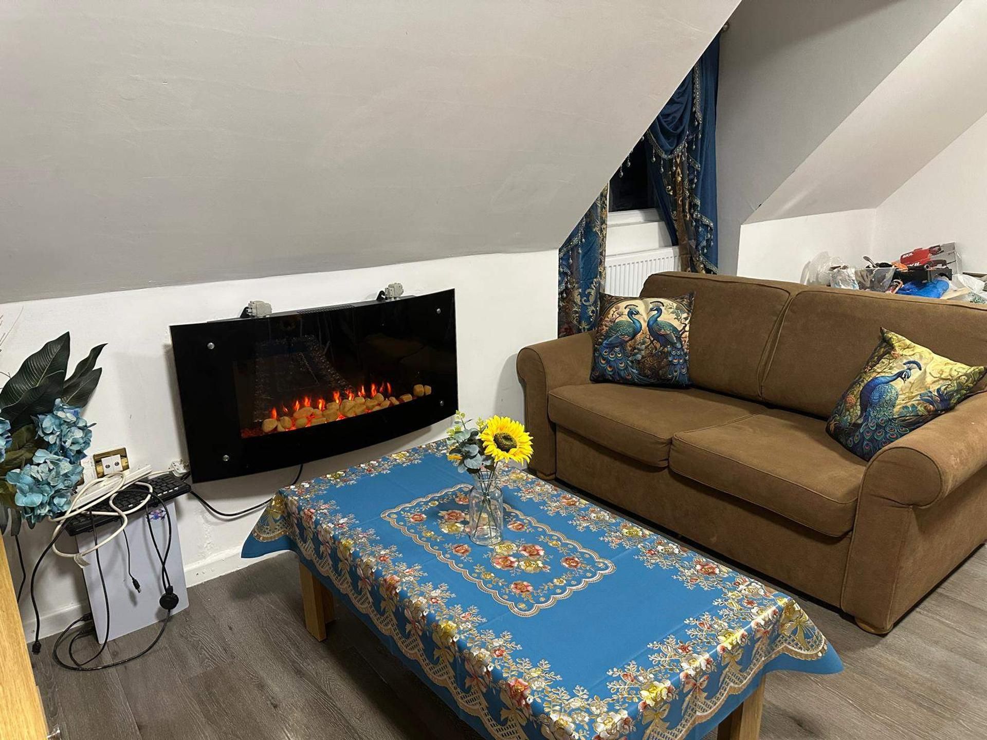 Uma sala de estar com sofá, mesa de centro, televisão de tela plana e lareira.