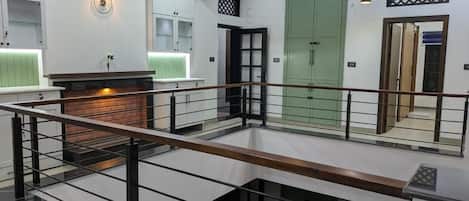 Um interior em vários níveis com uma escadaria central, lareira e porta verde.