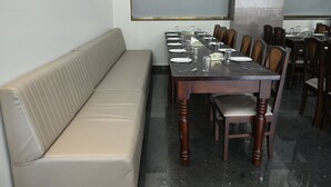 Uma sala de jantar com uma mesa comprida posta para refeição, rodeada por cadeiras.