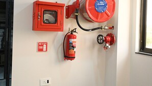 Extintor de incêndio fixado na parede, alarme de incêndio e detector de fumaça.