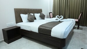 Cama bem arrumada com cabeceira, travesseiros e cobertor.