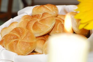 Uma cesta branca cheia de pães brancos e dourados.