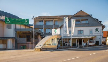 Hotel com fachada moderna, várias varandas e entrada imponente com toldo de vidro.