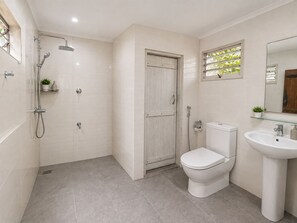 Casa de banho com chuveiro, sanita e lavatório, tudo num esquema de cores neutras.