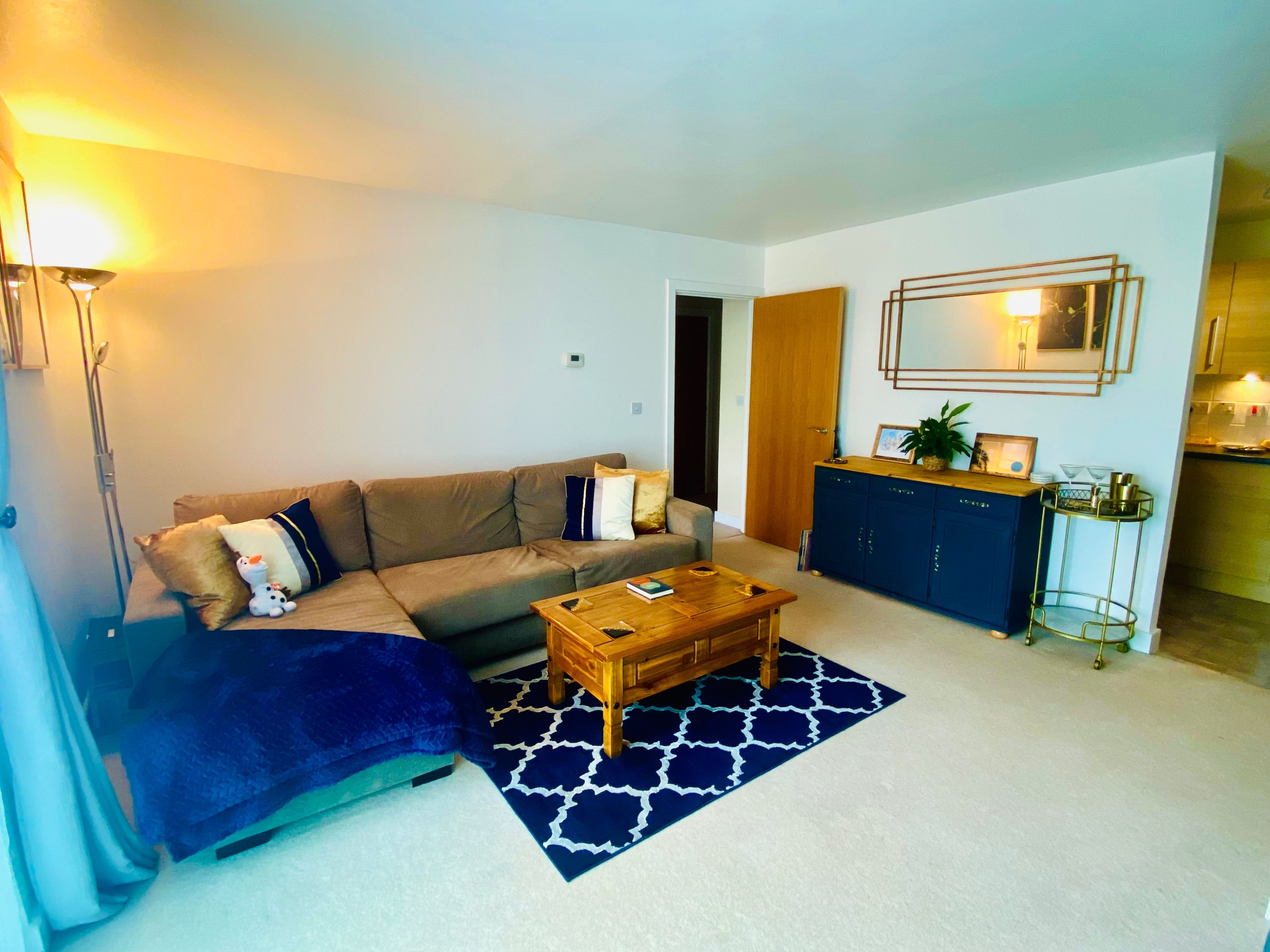 Uma sala de estar com sofá, mesa de centro e tapete azul estampado.