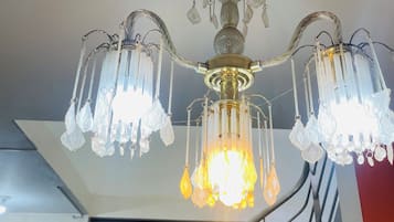 Um candelabro com vários elementos de cristal e uma fonte de luz central, pendurado no teto de um quarto com escada.