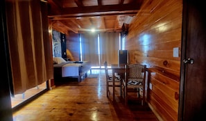 Interior de madeira com uma cama, uma mesa e cadeiras.