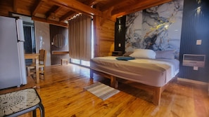 Quarto com estrutura de madeira, cama, escrivaninha e cadeira.