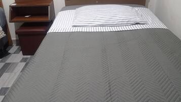 Uma cama com colchão estampado em padrão geométrico, travesseiro listrado e cabeceira com design geométrico.