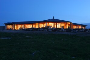 Uma casa moderna com um alpendre amplo, lareira de pedra e gramado bem cuidado.