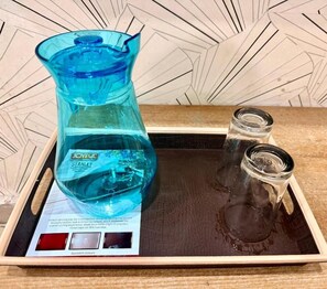 Uma bandeja com um jarro de vidro azul, duas garrafas de vidro pequenas e um rótulo com texto.