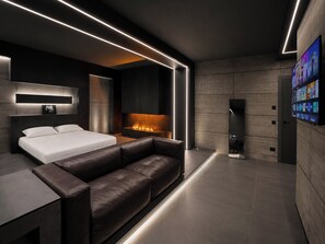 Quarto moderno com cama, sofá de couro, lareira e televisão na parede.