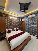 Quarto de hotel com cama, ventilador de teto, ar condicionado e papel de parede estampado.