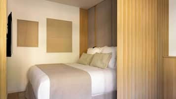 Quarto com cama, guarda-roupa de madeira e duas molduras na parede.