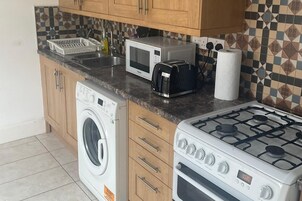 Cozinha compacta com máquina de lavar, torradeira, micro-ondas e fogão a gás.