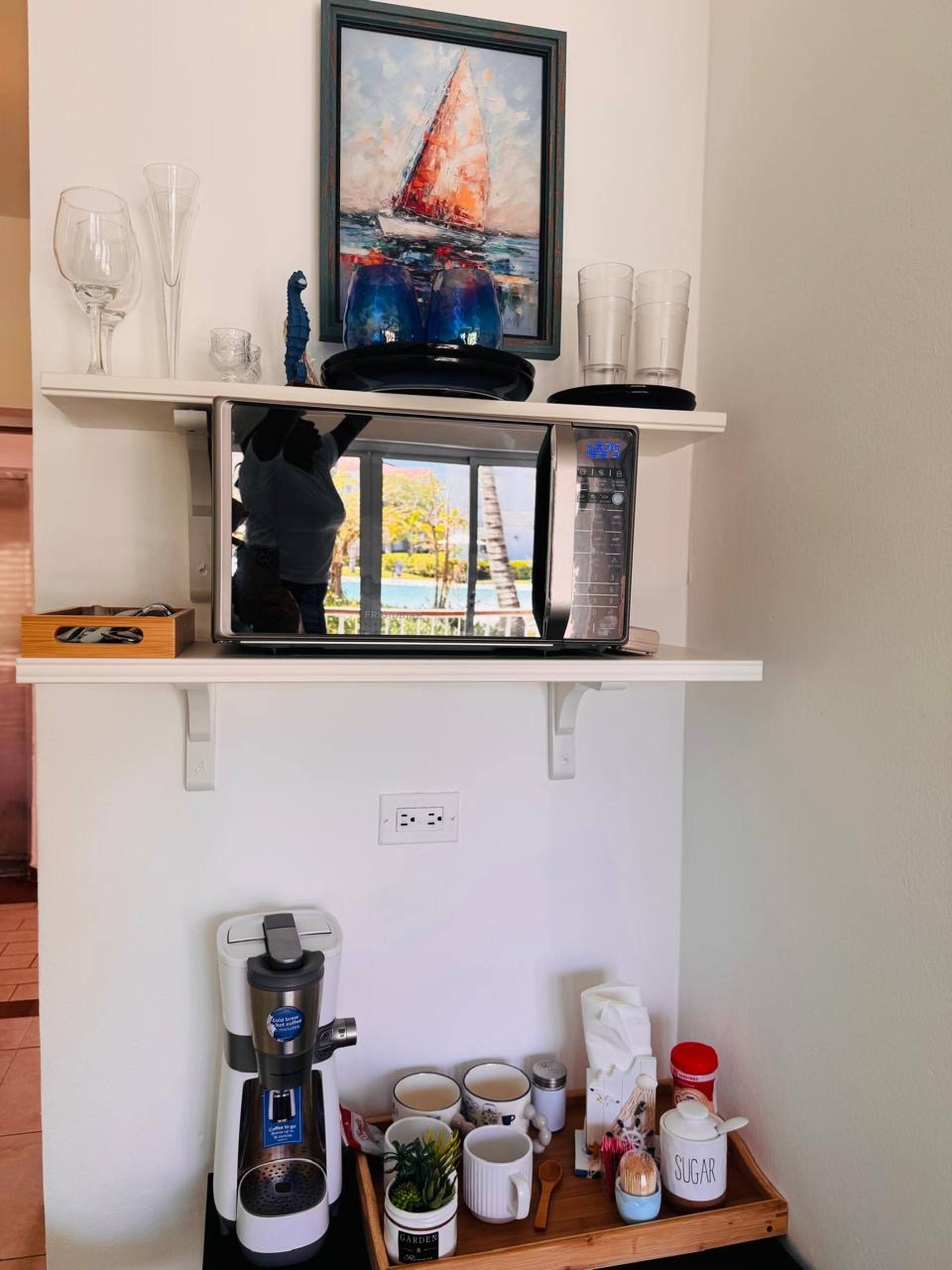 Uma área de cozinha com cafeteira, açúcar e chávenas numa bandeja.