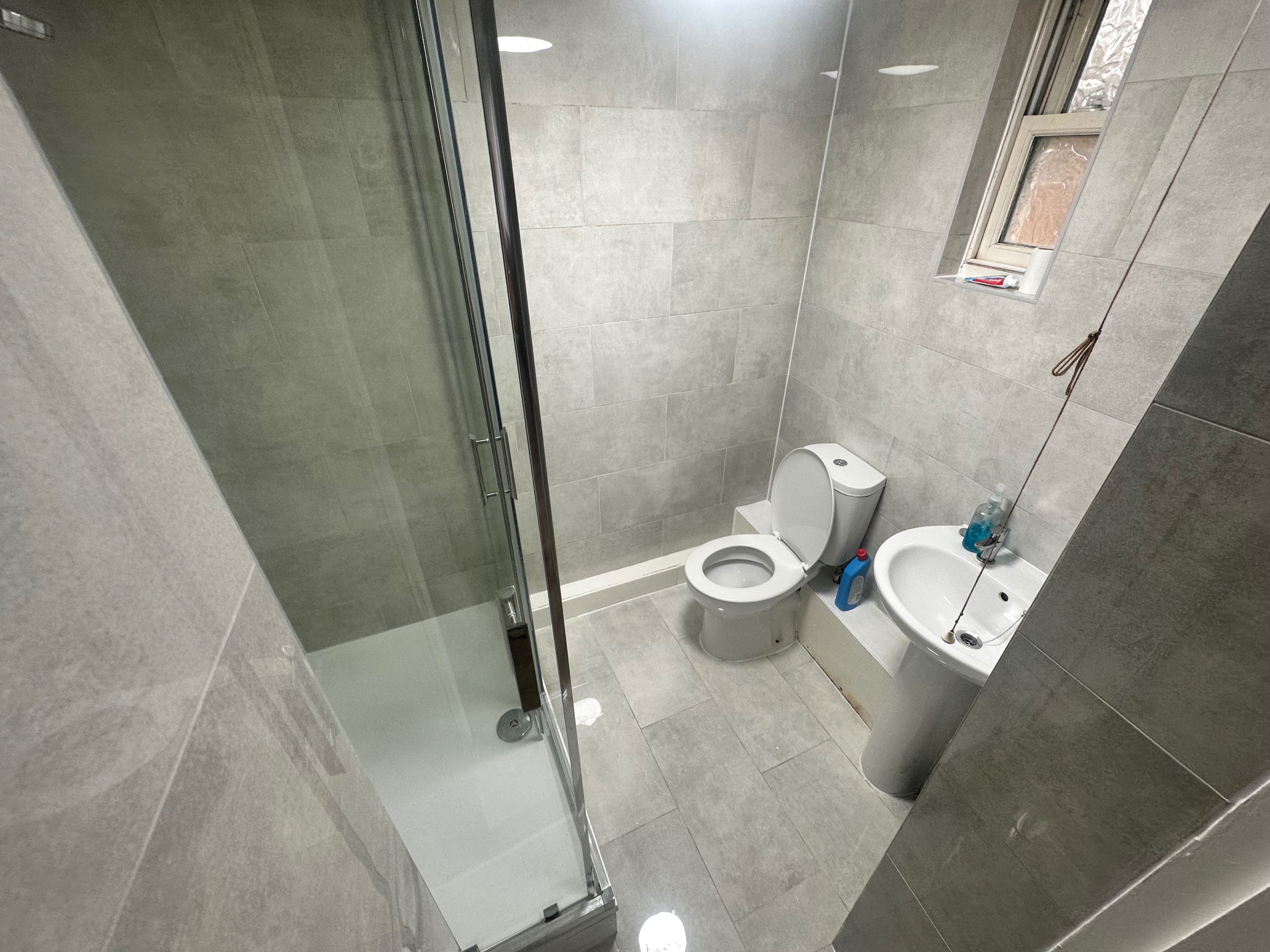 Um banheiro moderno com box de vidro, vaso sanitário e pia sobreposta.