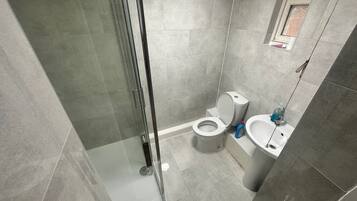 Um banheiro moderno com box de vidro, vaso sanitário e pia sobreposta.