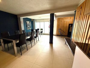 Uma área de refeições moderna, com mesa e cadeiras pretas, uma parede de destaque azul e um painel de madeira.