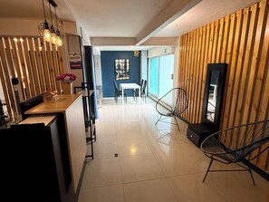 Um interior moderno com cozinha, espaço de refeições e sala de estar, incluindo TV e assentos.