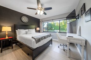 Quarto moderno com cama, luminárias de cabeceira, escrivaninha e ventilador de teto.
