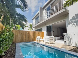 Uma casa moderna com piscina, área de estar externa e cerca de madeira.