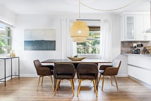 Cozinha moderna com mesa de jantar, cadeiras e luminária pendente.