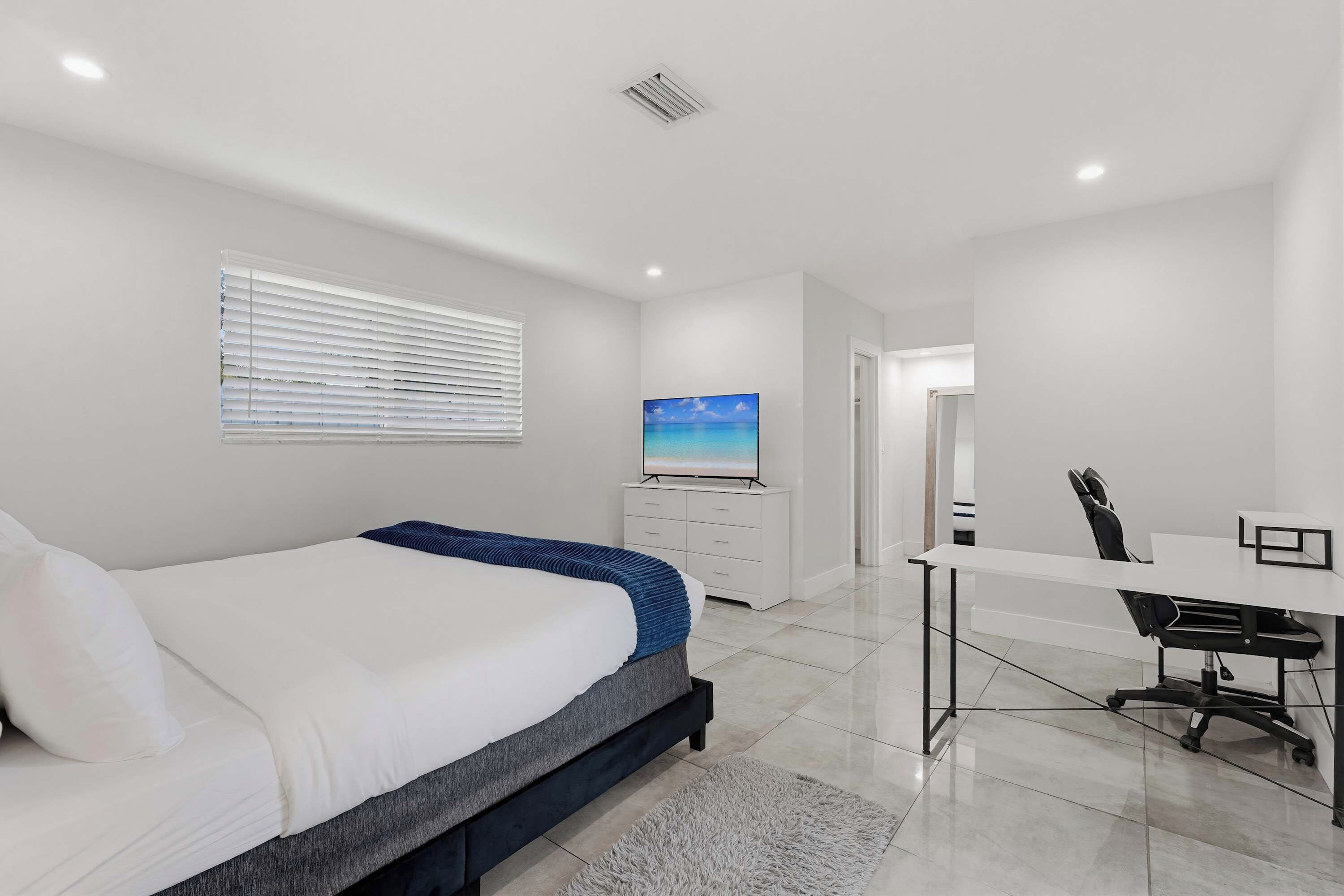 Quarto com uma cama, uma escrivaninha e uma televisão.