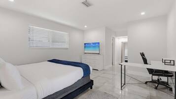 Quarto com uma cama, uma escrivaninha e uma televisão.