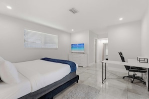 Quarto com uma cama, uma escrivaninha e uma televisão.